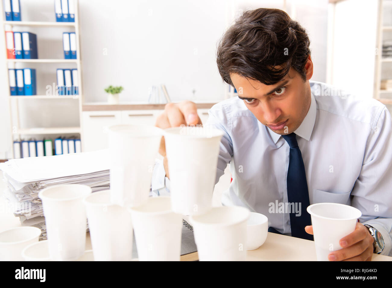 Young employee building pyramid from plastic cups Stock Photo - Alamy