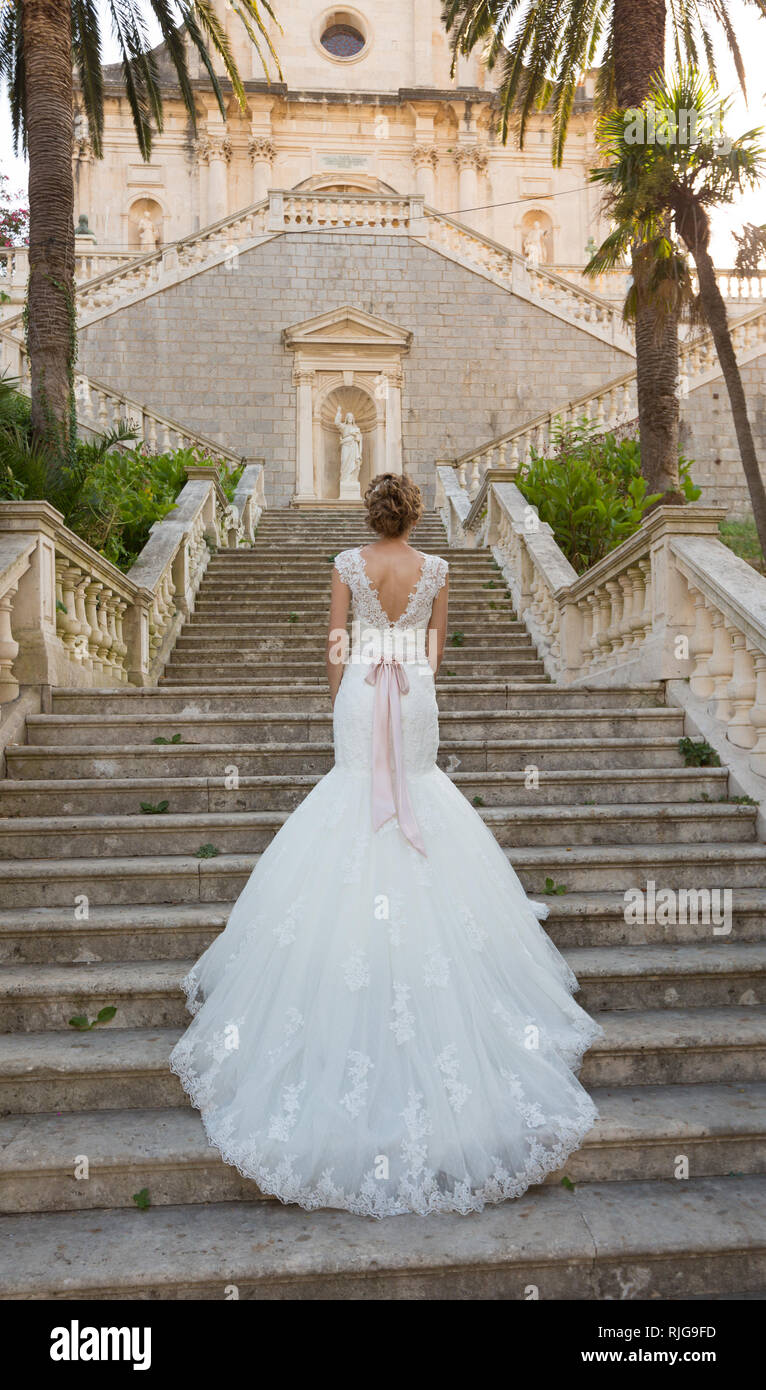graceful bride climbs the stone stairs in a wedding dress Stock Photo ...