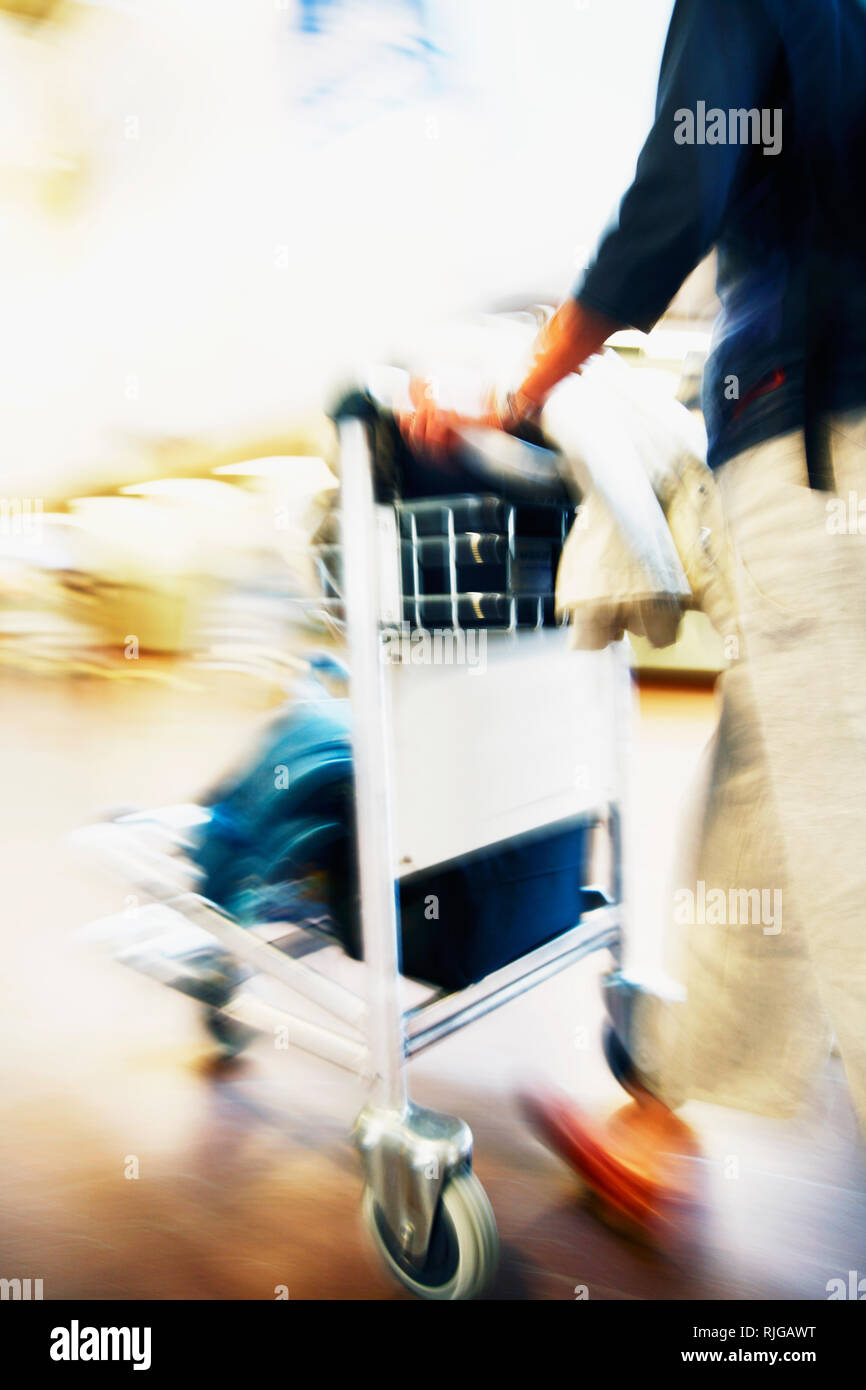 Woman pushing trolley at airport Stock Photo - Alamy