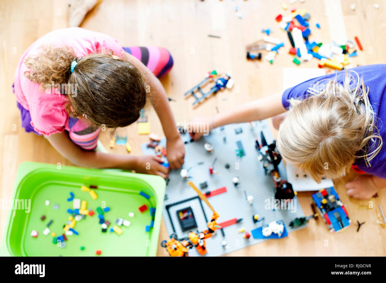 Girls playing with toy blocks on floor Stock Photo - Alamy