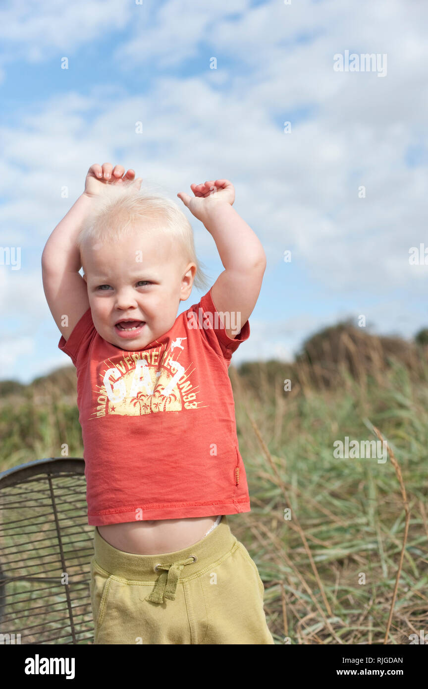 Cute boy standing in meadow with arms raised Stock Photo - Alamy