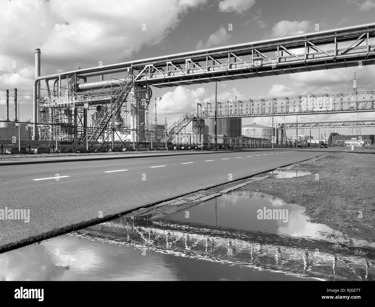 Oil refinery with scaffolds and crossing pipelines reflected in a pond ...