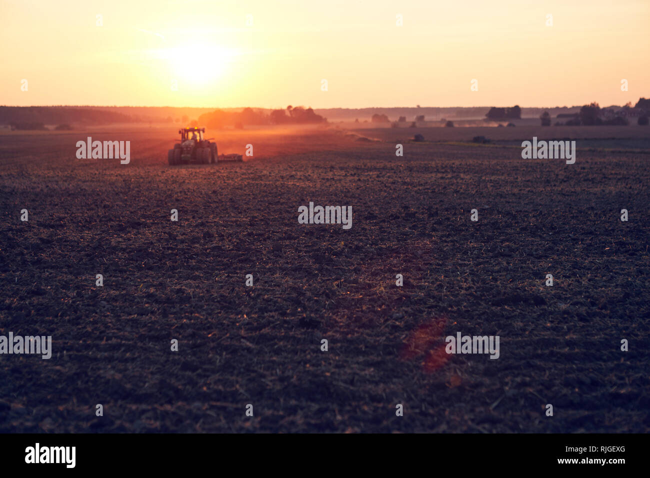 Tractor on field at sunset Stock Photo - Alamy