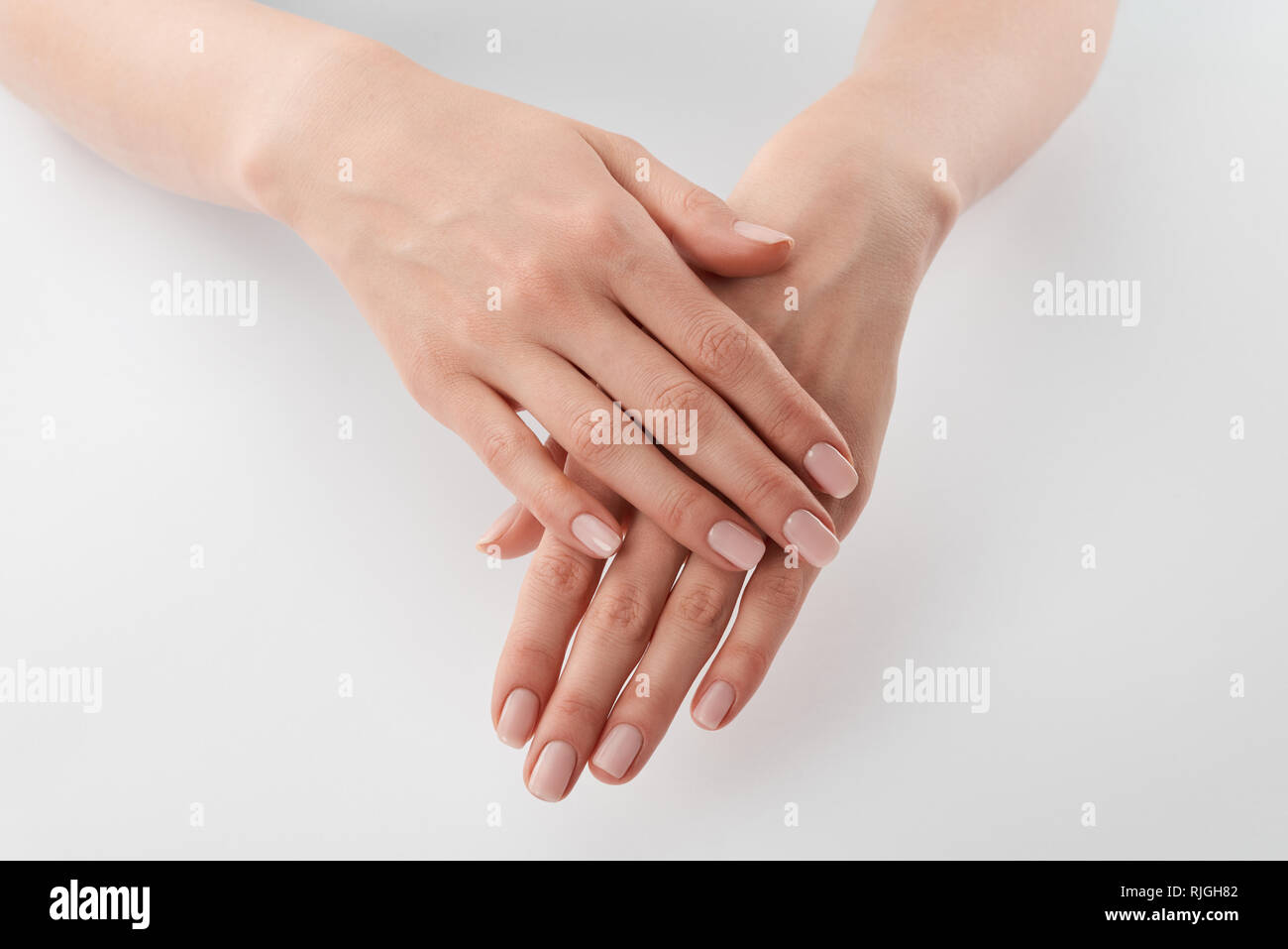 Partial view of female well-cared clanched hands on white background ...