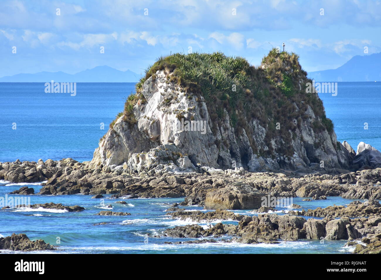 Large rock formation in blue sea near sea shore eroding under elements ...