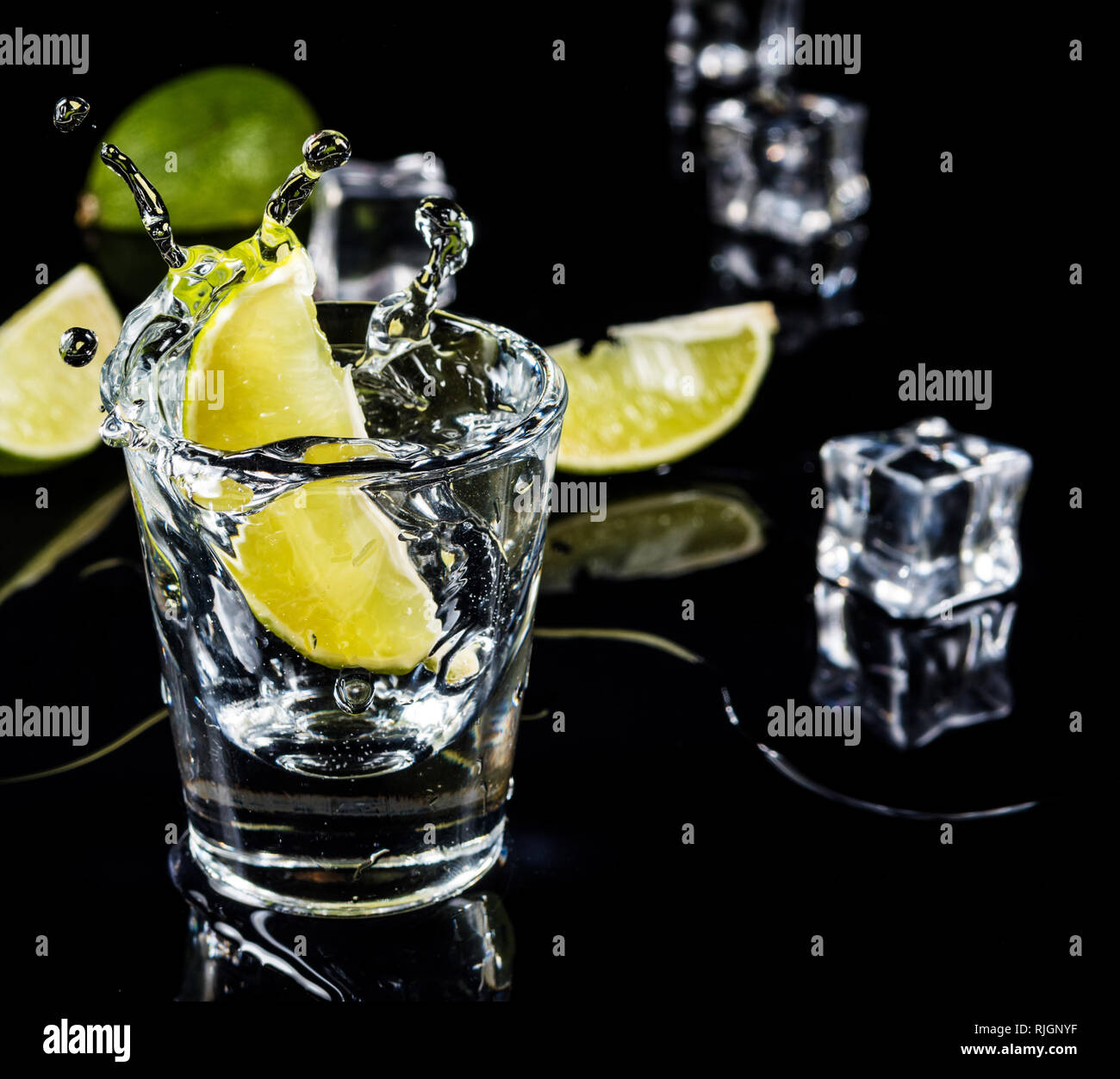 Mexican traditional Tequila splash lime on black background with ice ...