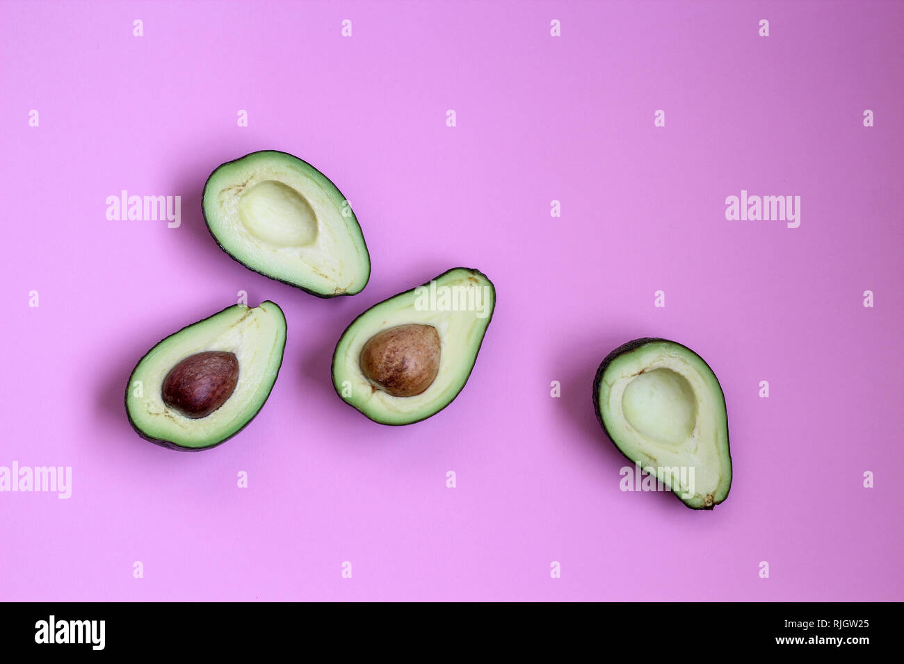 Cut avocados on pink background Stock Photo - Alamy