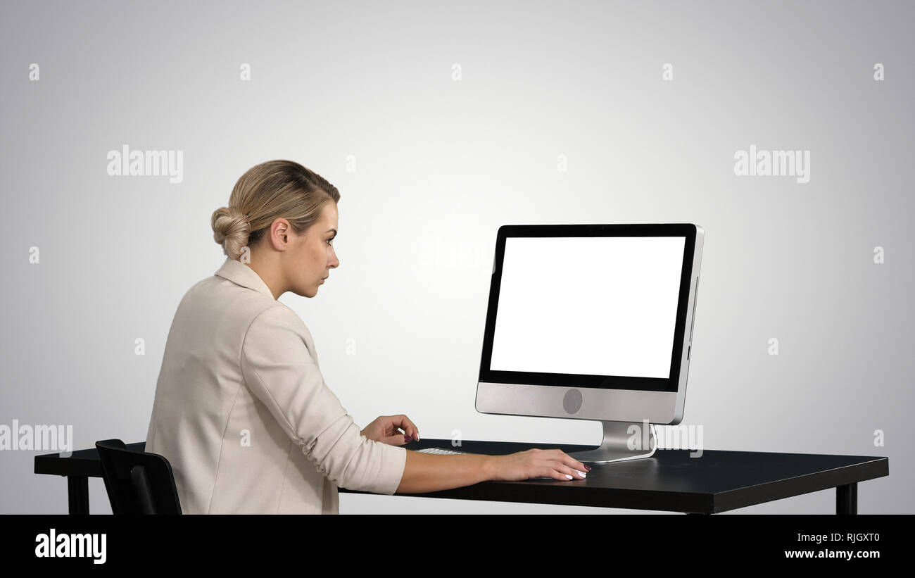 Business person works at table with computer on gradient background ...