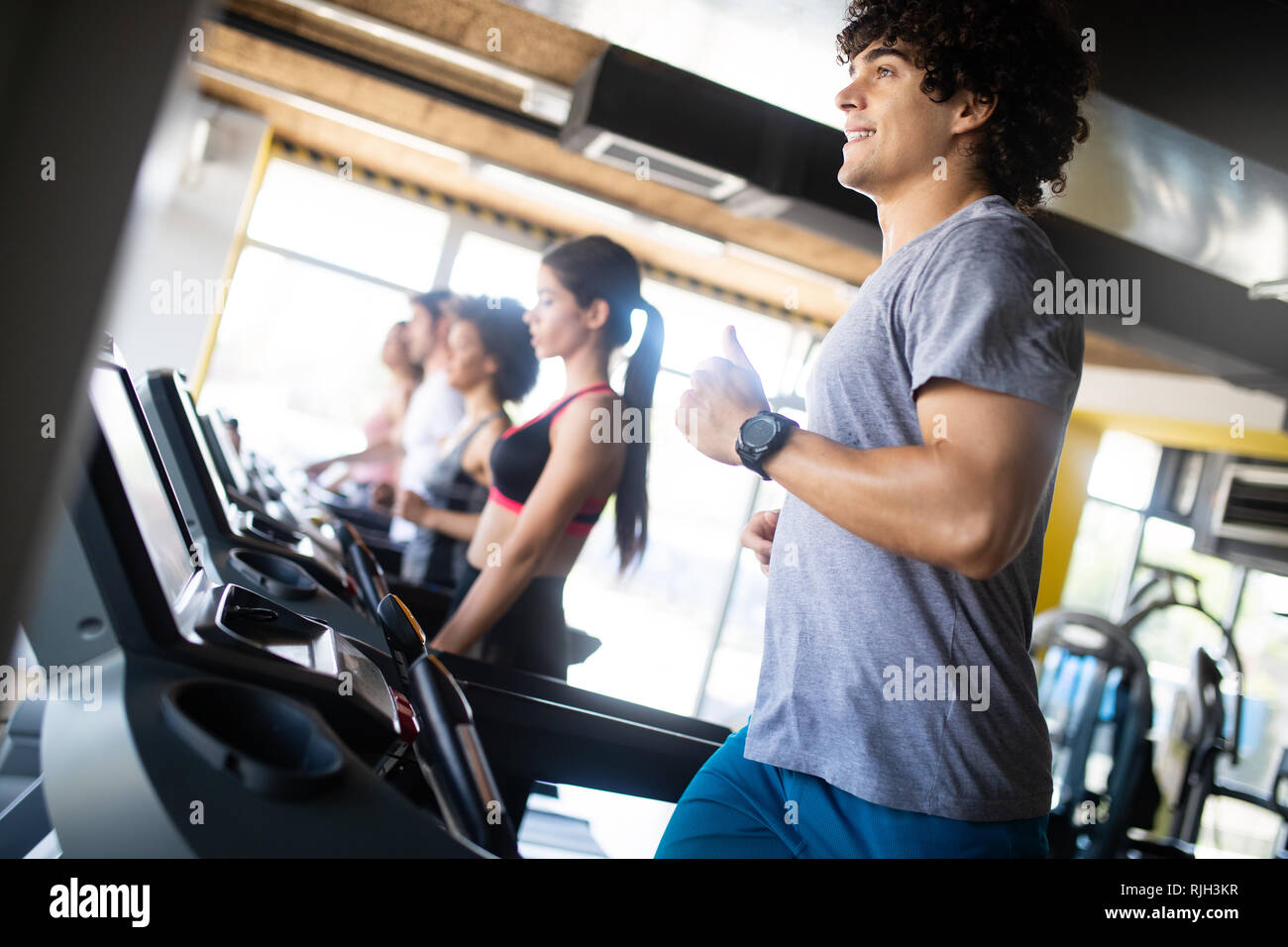 Happy fit people running on treadmill at fitness gym club Stock Photo ...