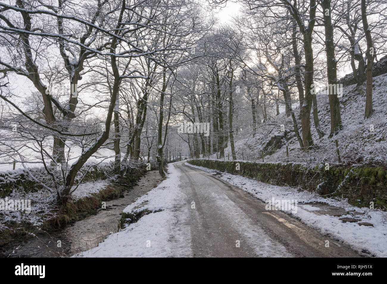 Icy road in the British countryside on a cold winter morning. Hayfield ...