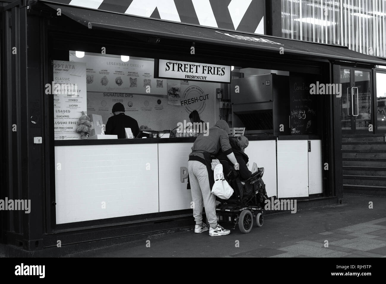 Pop up owner helps disabled person in wheelchair in Croydon Stock Photo ...