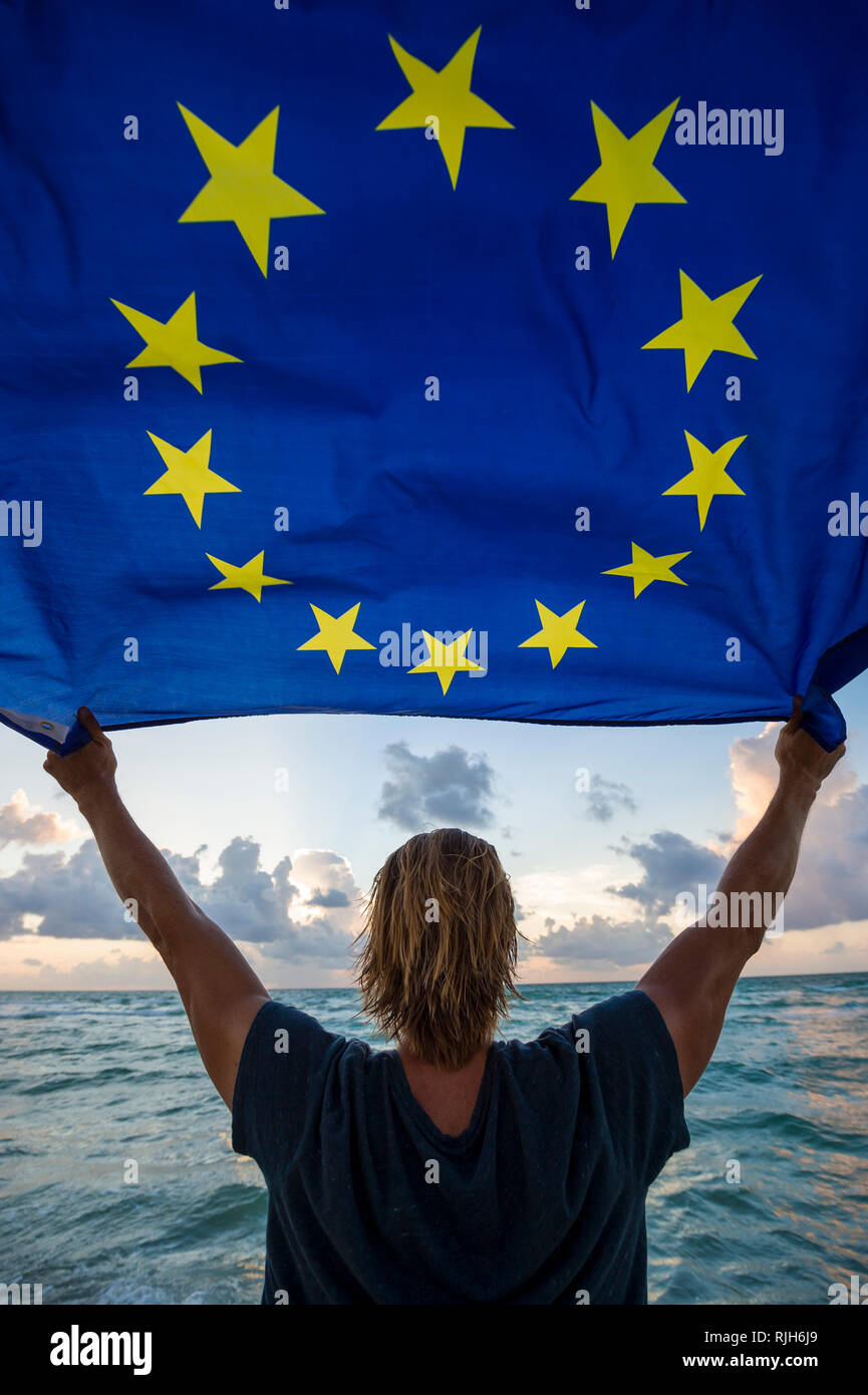 European Union flag flying in bright morning sunlight held up by man ...
