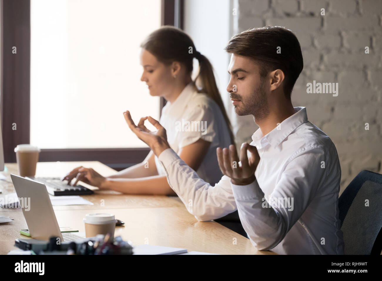 Calm male employee sit near computer meditating at workplace Stock ...