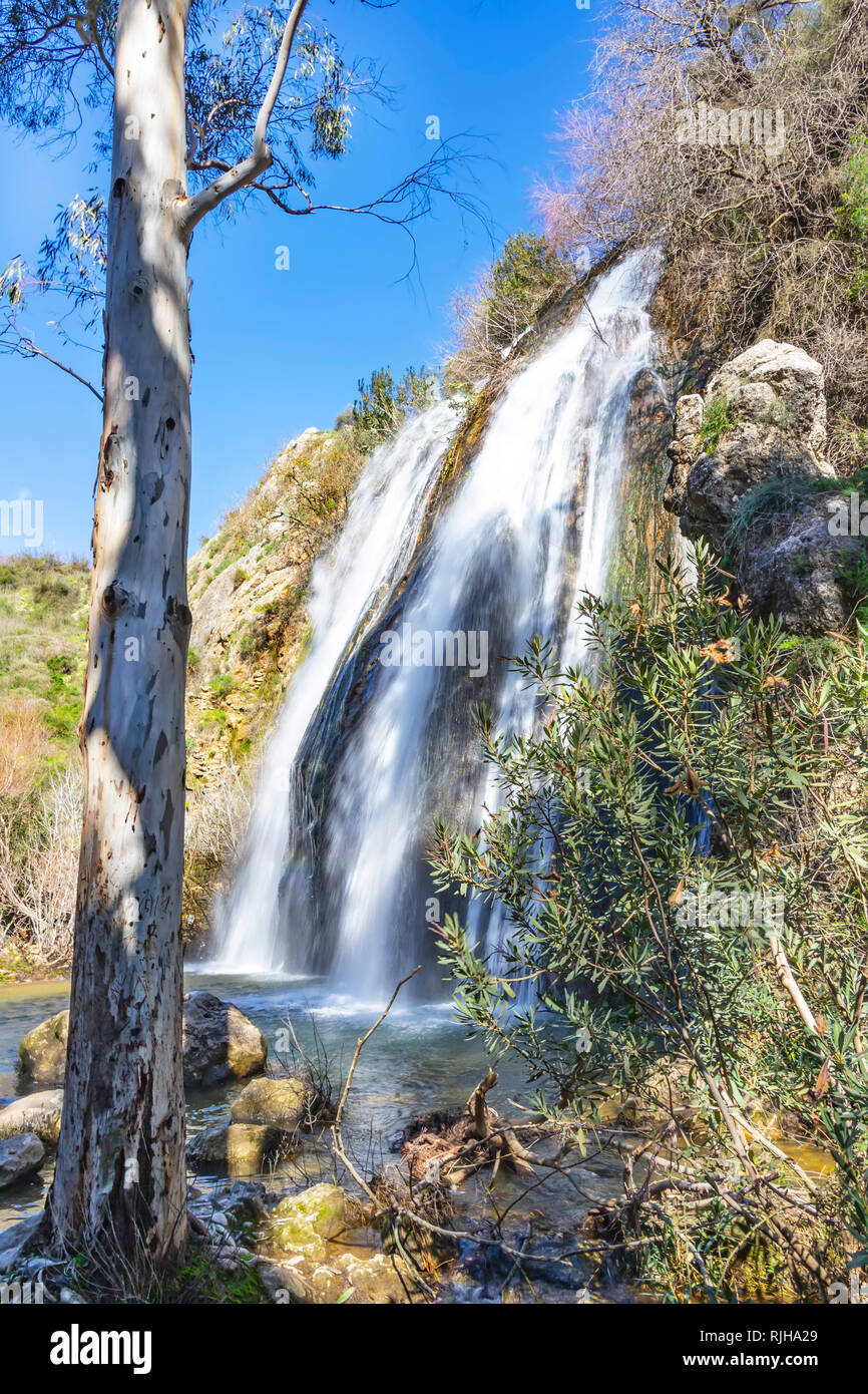 Side view of the waterfall and the pond in front of it among the autumn ...