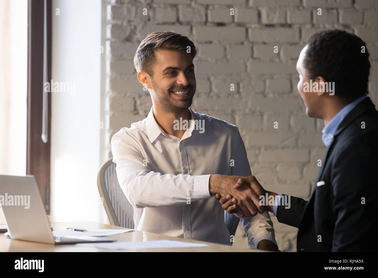 Excited businessman handshake male applicant at job interview Stock ...