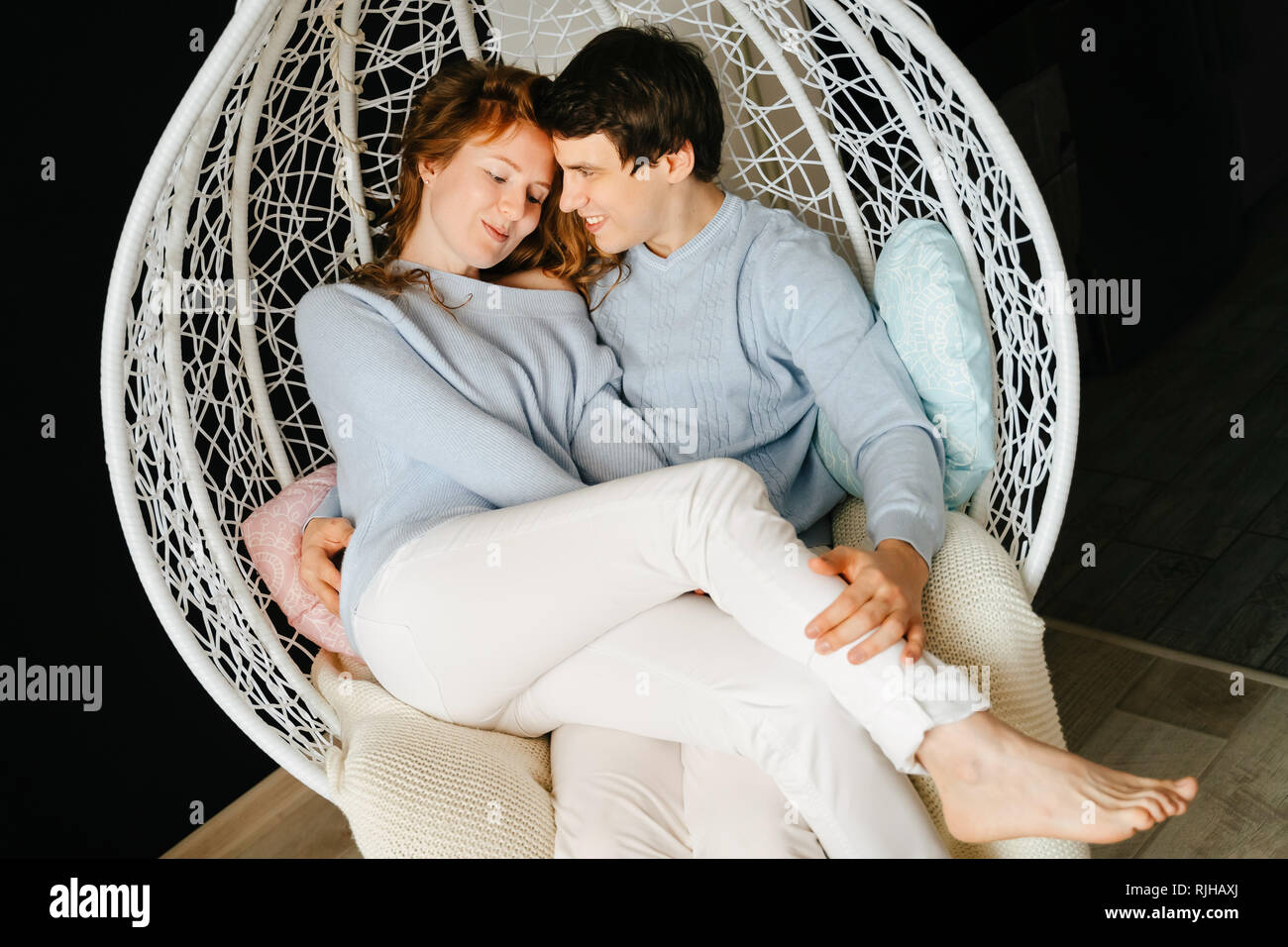 Couple girl and guy hugging on a big chair Stock Photo - Alamy