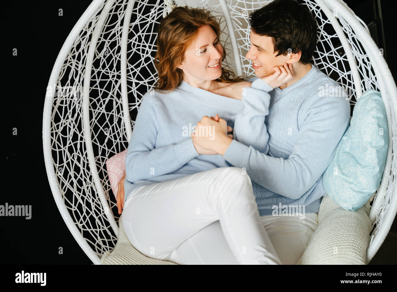 Couple girl and guy hugging on a big chair Stock Photo - Alamy