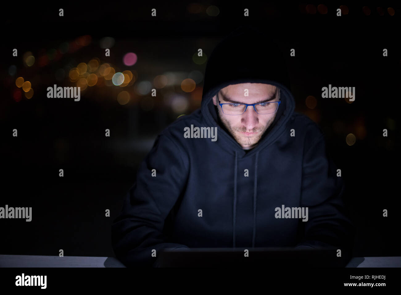 Young talented hacker using laptop computer while working in dark ...