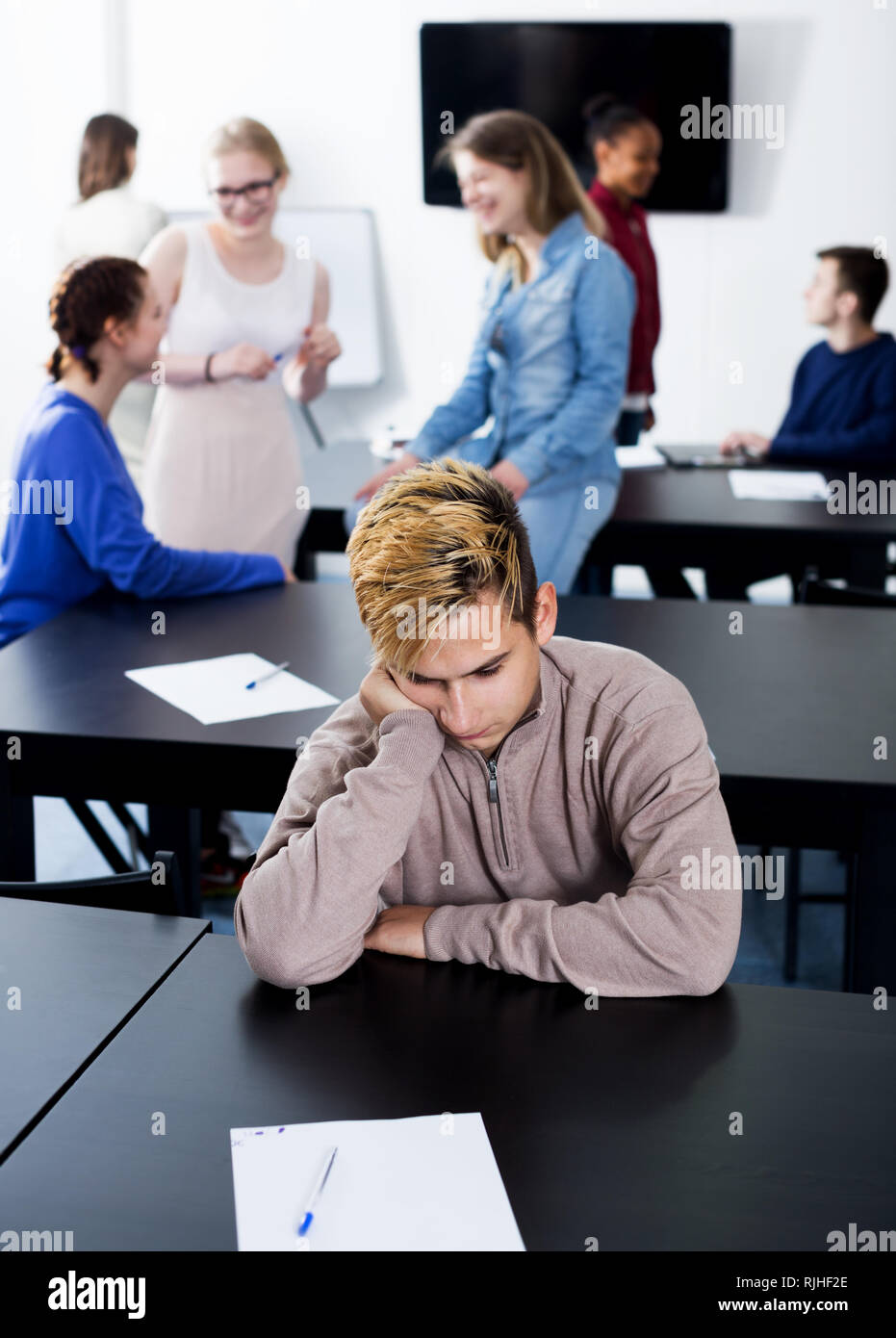 Unhappy new boy student being shy among classmates at recess in school ...