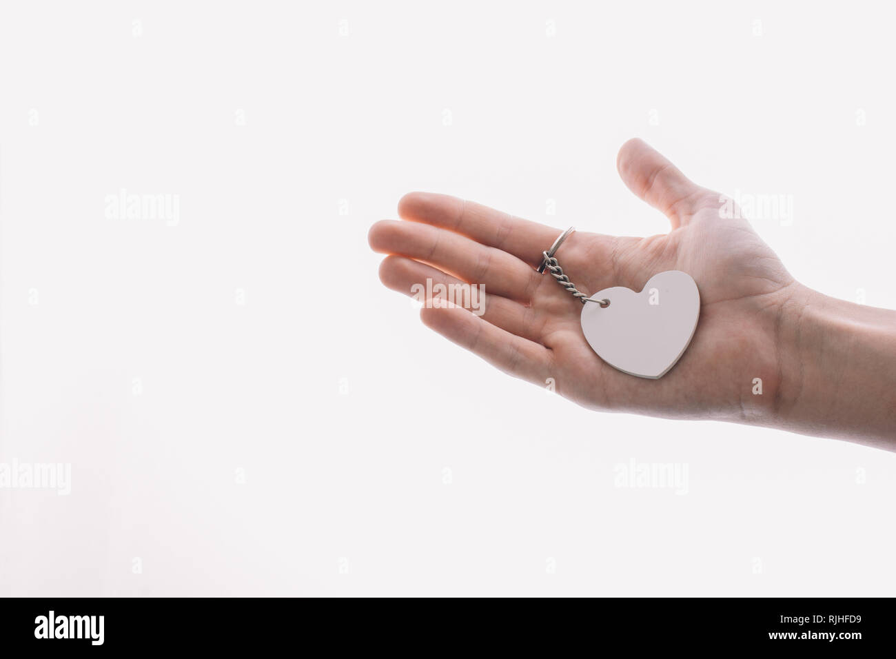 Heart shaped white object in hand on white background Stock Photo - Alamy