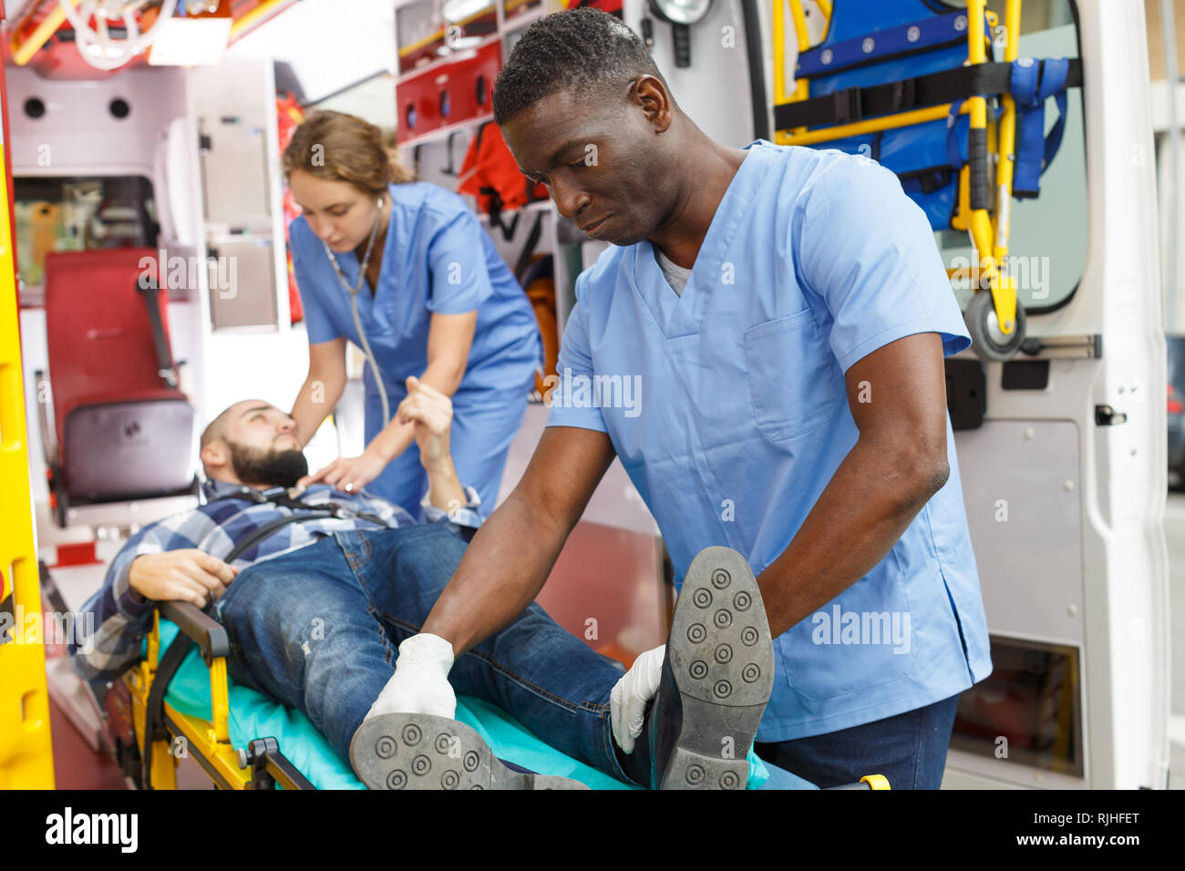 Paramedic team moving injured man on stretcher in ambulance auto Stock ...
