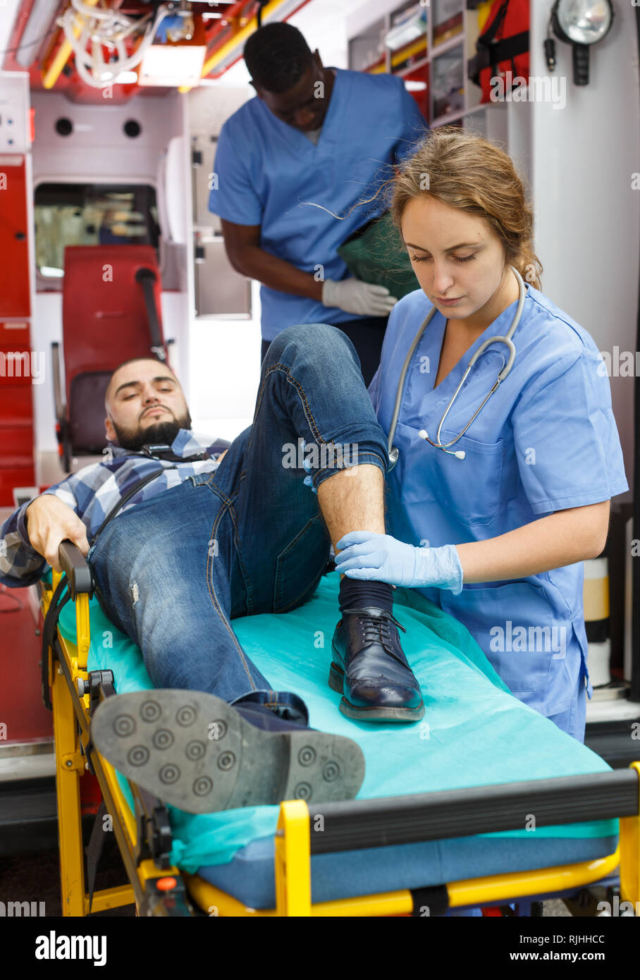 Emergency doctors providing medical care to injured man in ambulance ...
