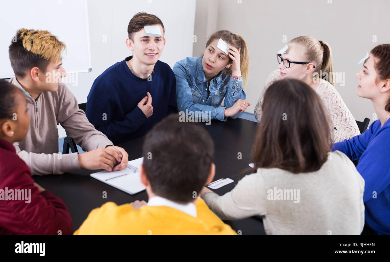 Happy male and female students playing guess-who game in school Stock ...
