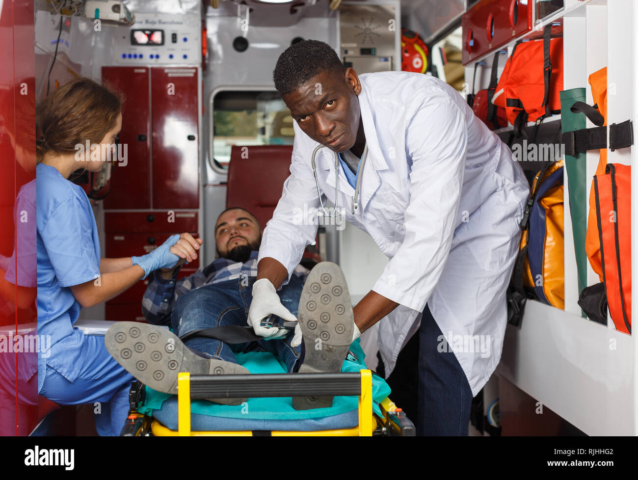 Emergency doctors fixing patient on stretcher in ambulance car Stock ...