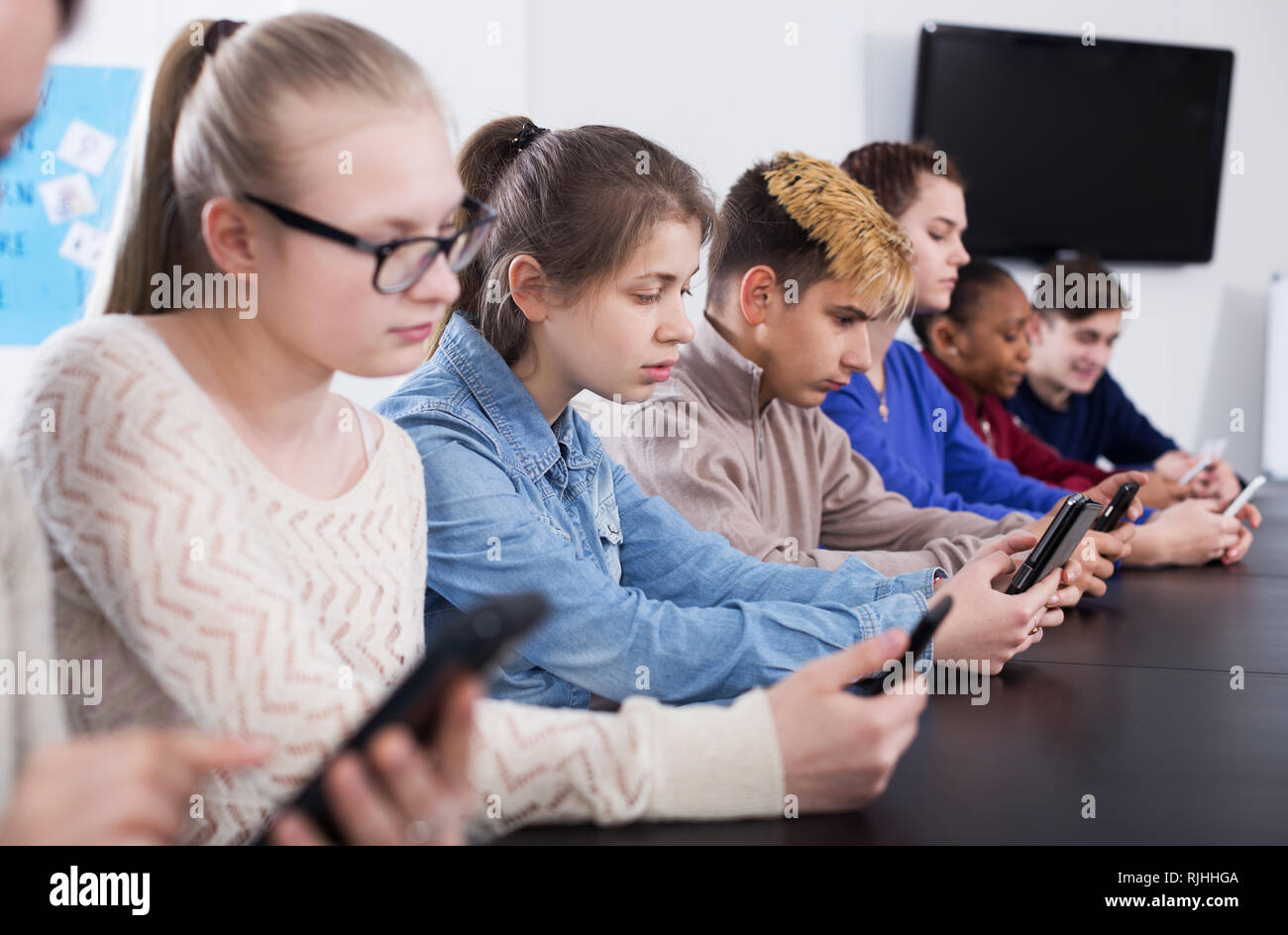 Positive young male and female students playing with their smartphones ...