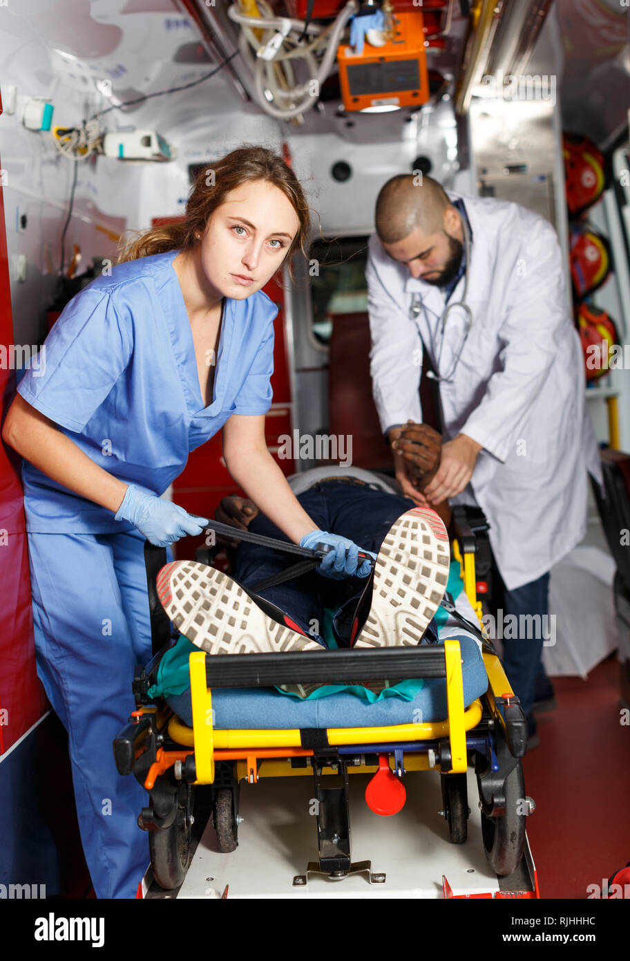 Paramedic team moving injured man on stretcher in ambulance auto Stock ...