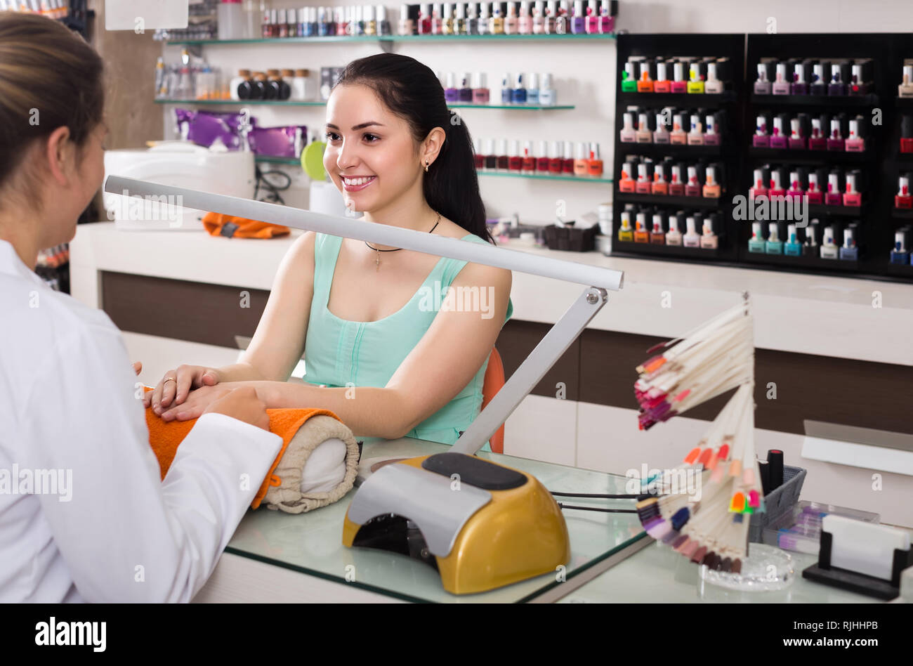 happy italian manicurists giving manicure to female clients at nail ...