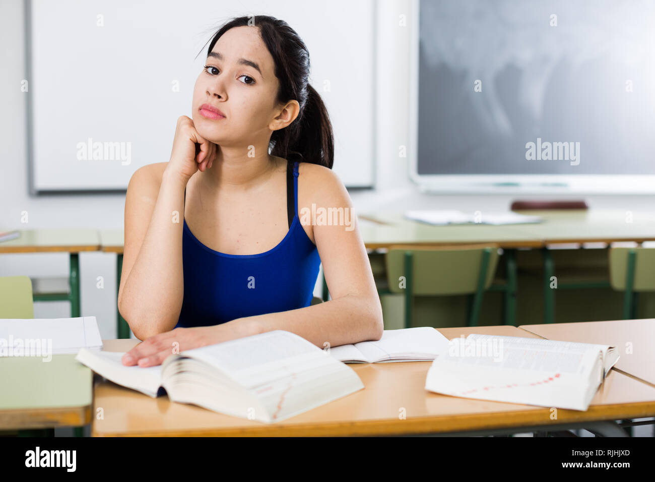 Young girl is thinking about difficult task at the desk in the class ...