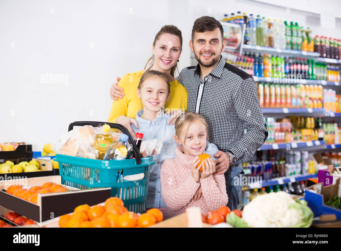 Cheerful parents with two kids during family shopping in vegetable ...