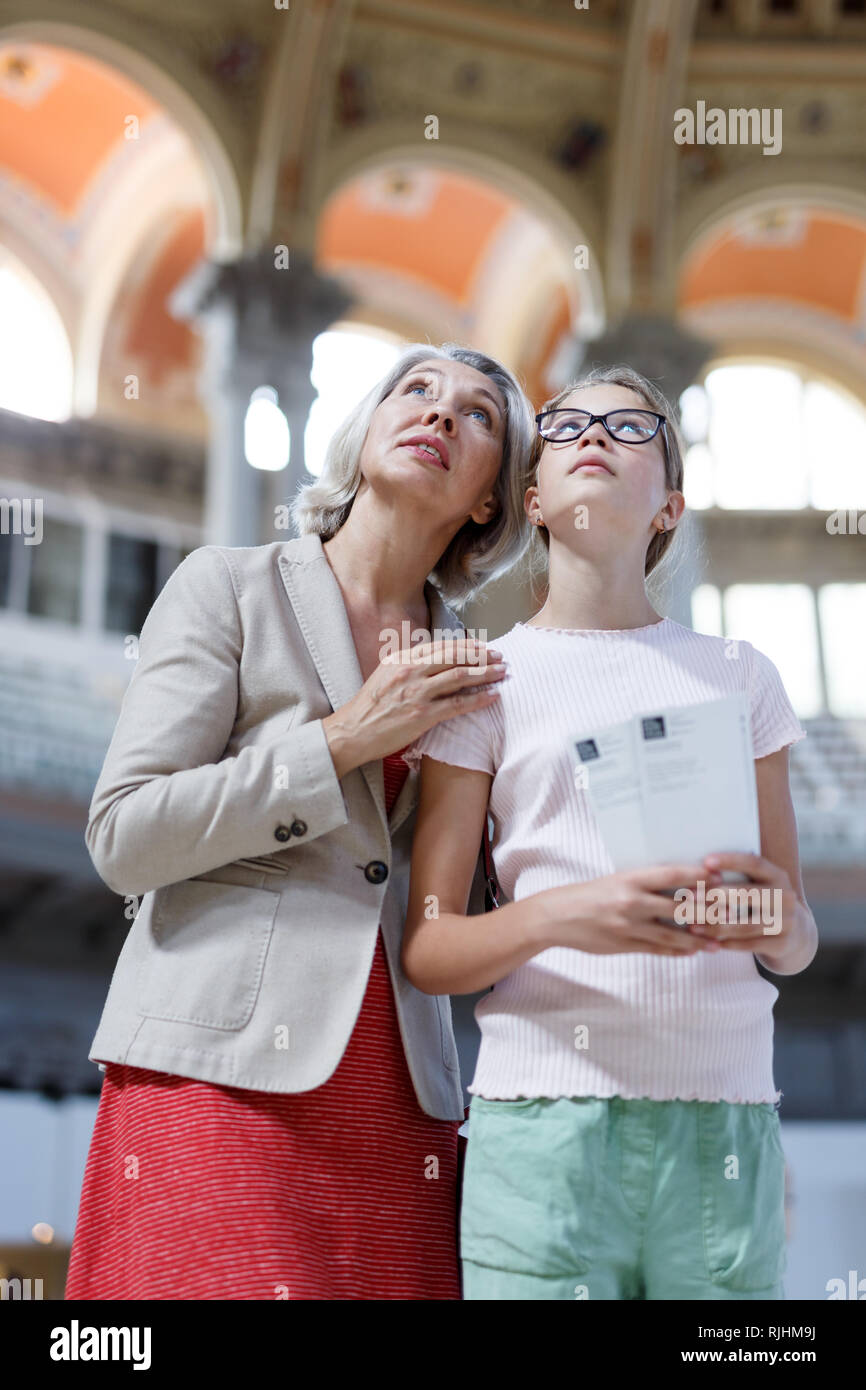 Attentive tween girl with senior woman looking with interest at gallery ...