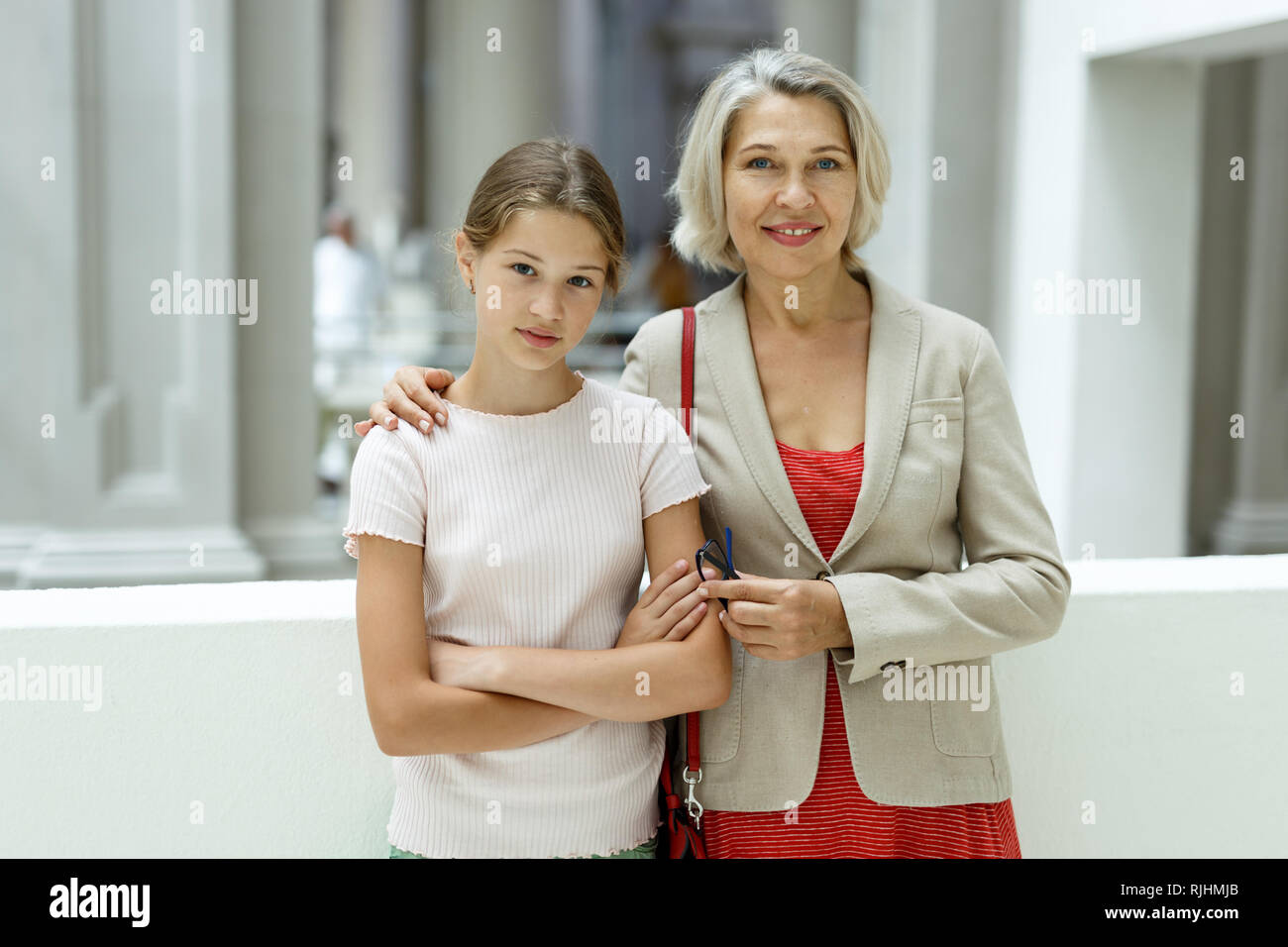 Attentive tween girl with senior woman looking with interest at gallery ...