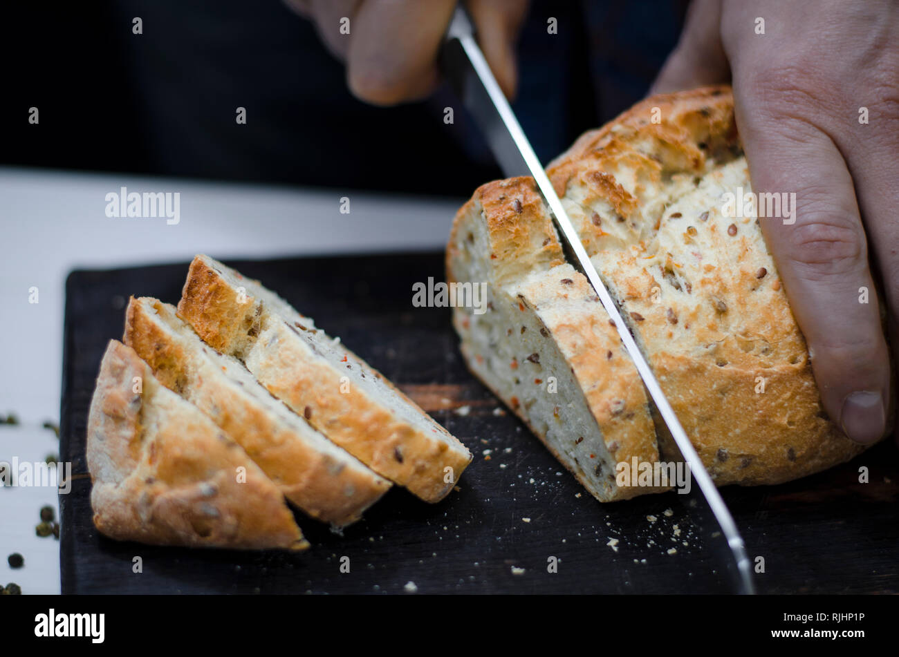 Whole grain bread put on kitchen wood plate with a chef holding gold ...