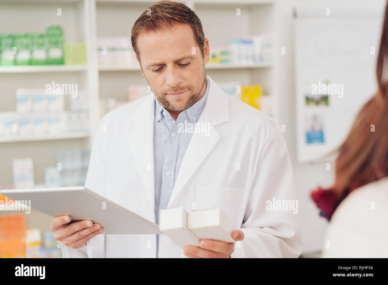 Pharmacist checking medicines before dispensing them to a waiting ...