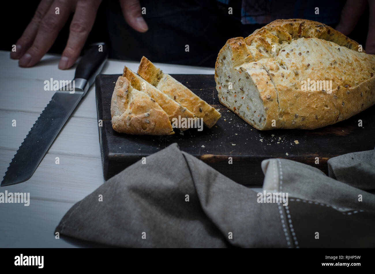 Whole grain bread put on kitchen wood plate with a chef holding gold ...