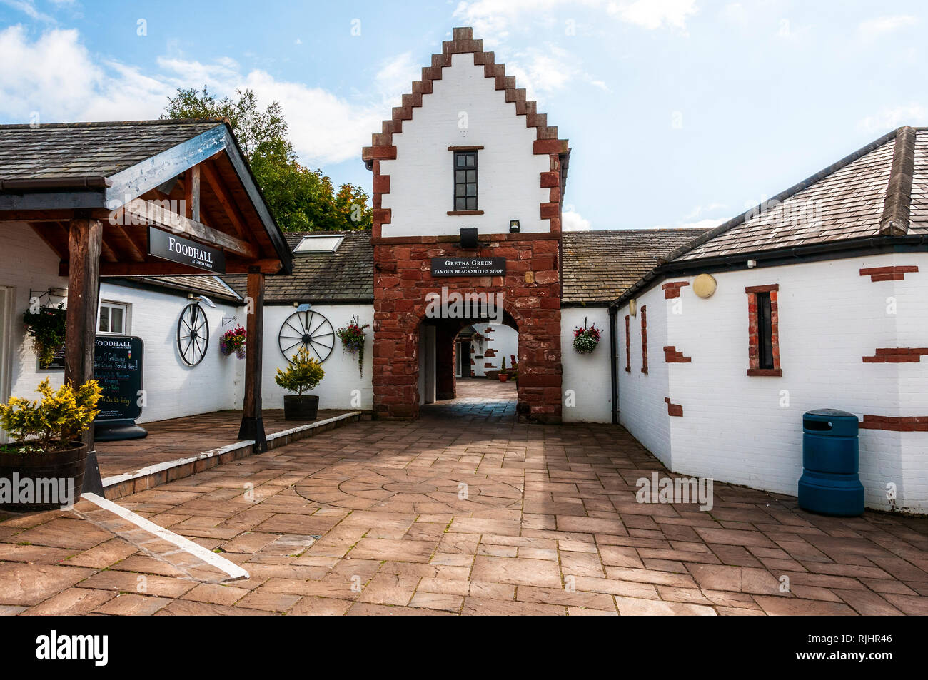 A pristine paved courtyard leads to a red brick archway through a tower ...