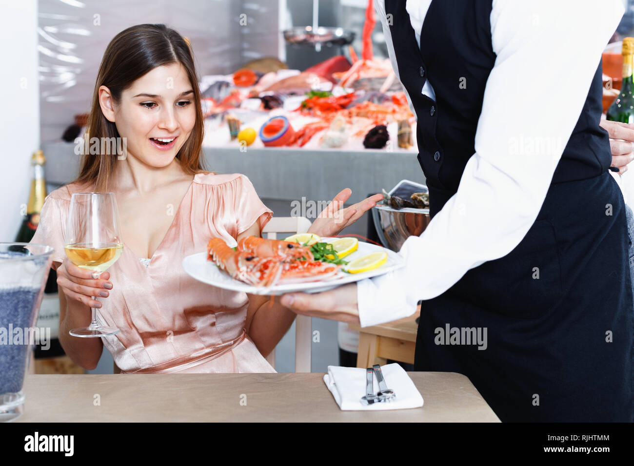 Young cheerful positive woman visiting fish restaurant pleasantly ...