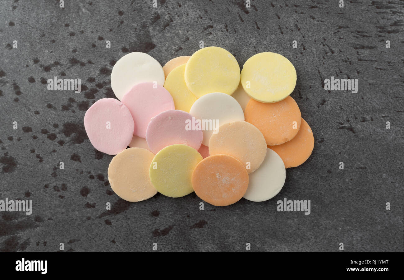Top view of several thin colorful candy wafers on a gray background ...