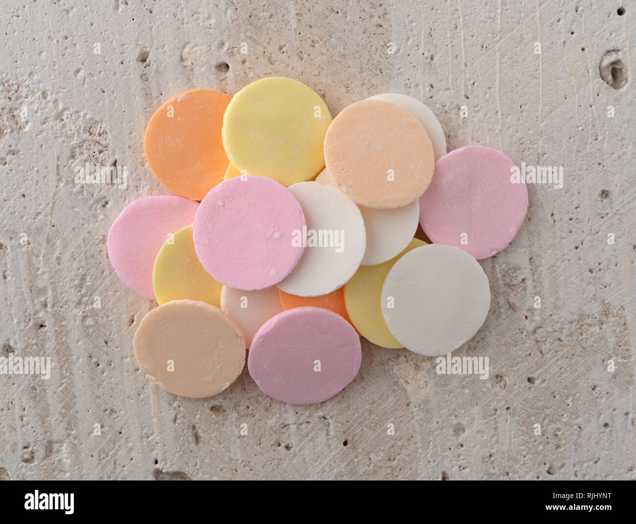 Top view of a small pile of thin colorful candy wafers on a rough ...
