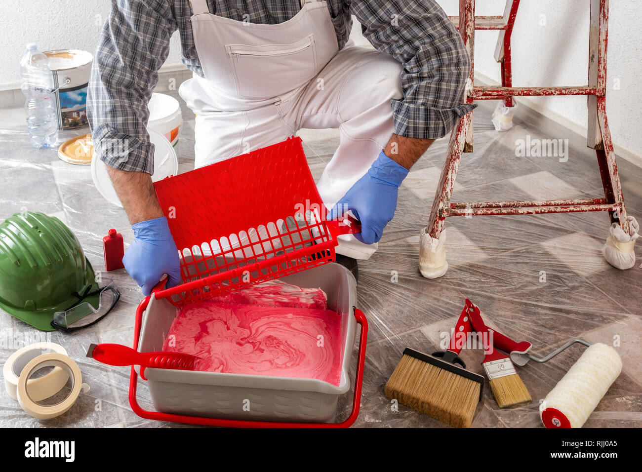 Caucasian house painter worker in white work overalls, prepare the ...