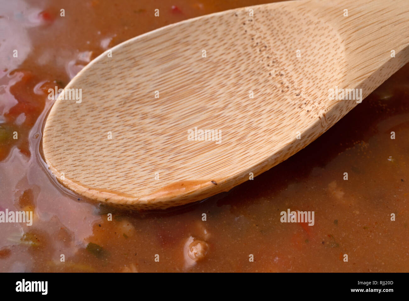 Chicken tortilla soup with a wood spoon on the food illuminated with ...