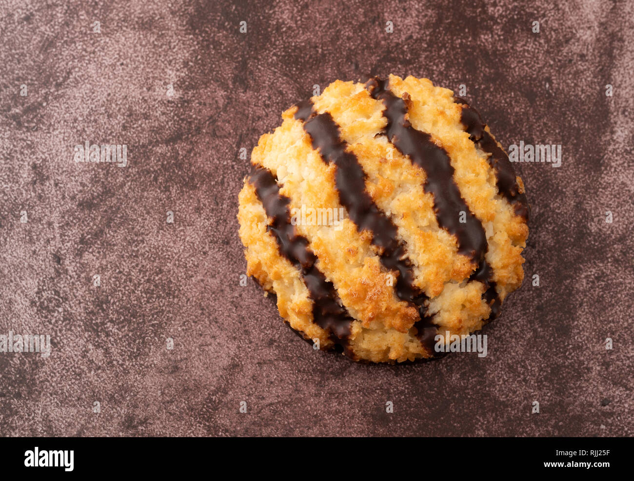 Overhead view of a single dark chocolate striped coconut macaroon on a ...