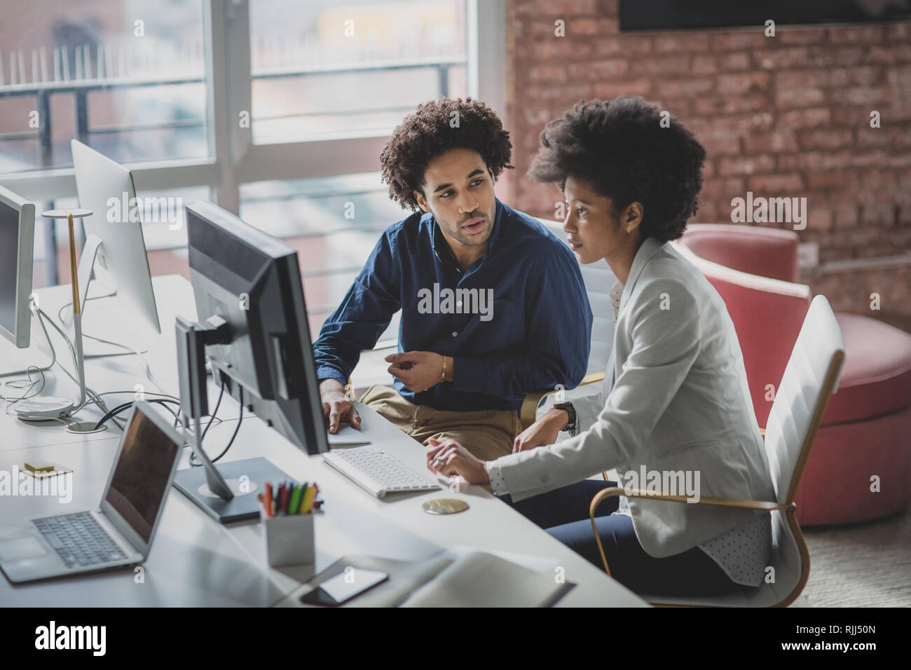 Coworkers looking at a desktop computer together Stock Photo - Alamy