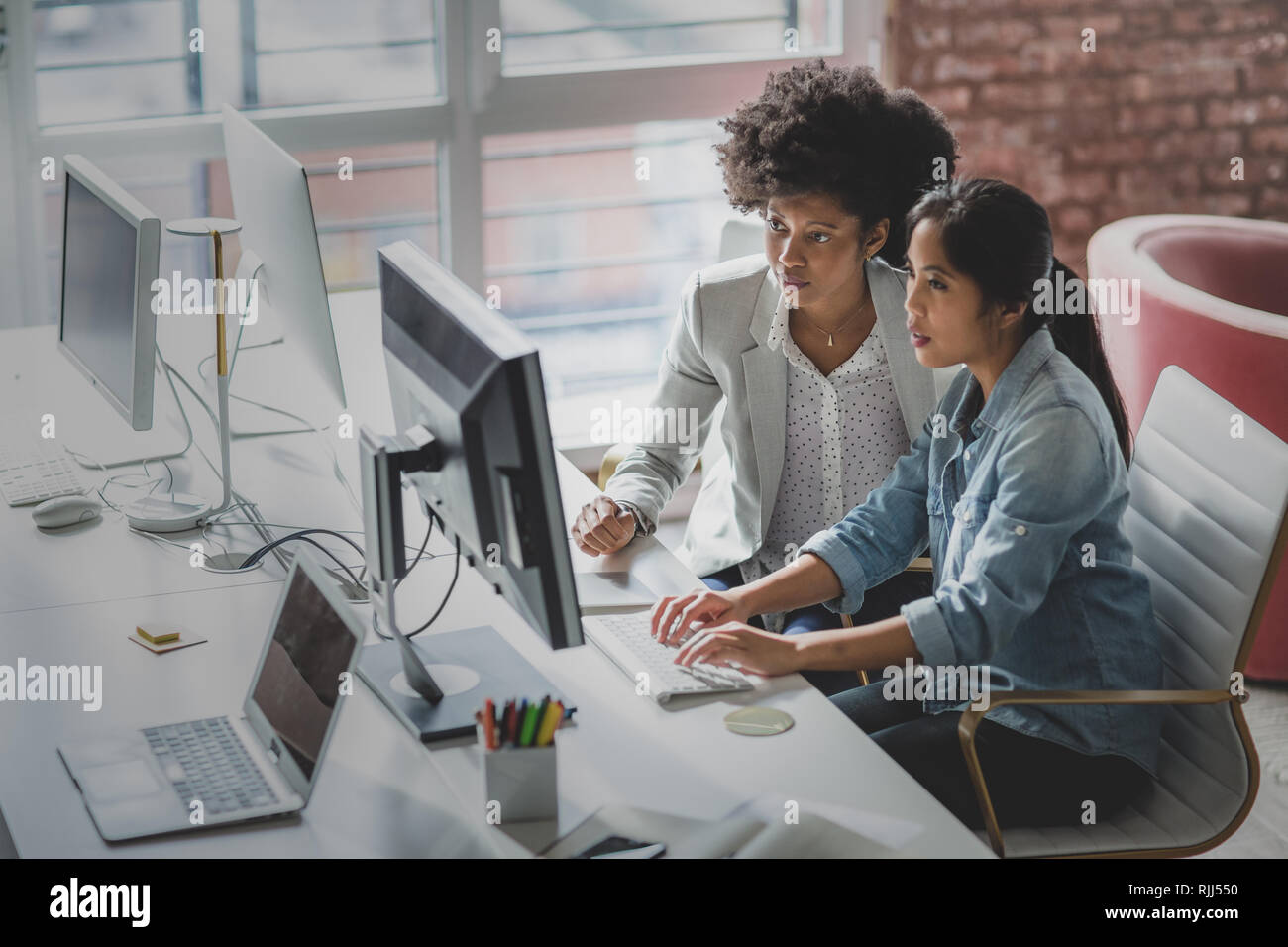 Coworkers looking at a desktop computer together Stock Photo - Alamy