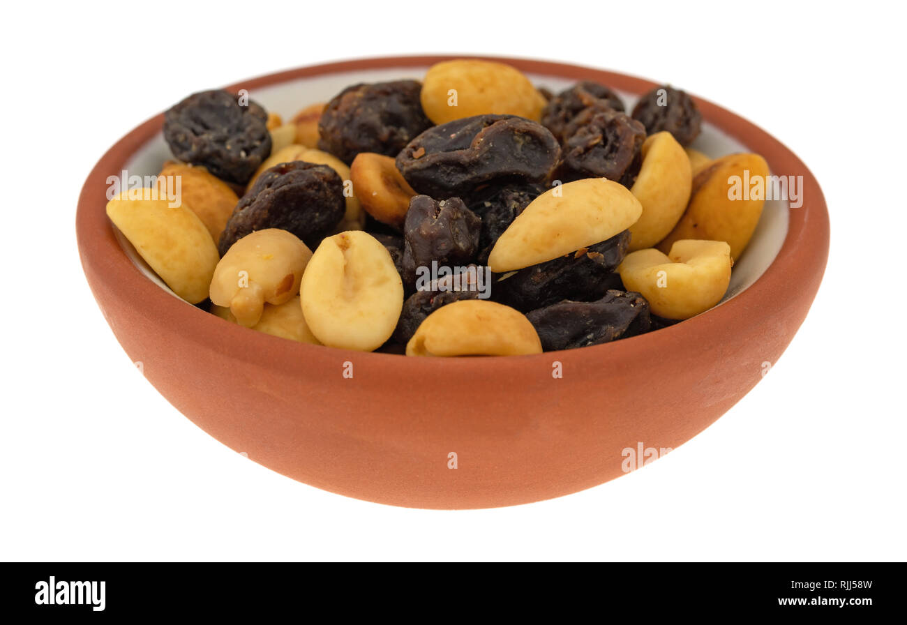 Side view of a small bowl filled with peanuts and raisins isolated on a ...