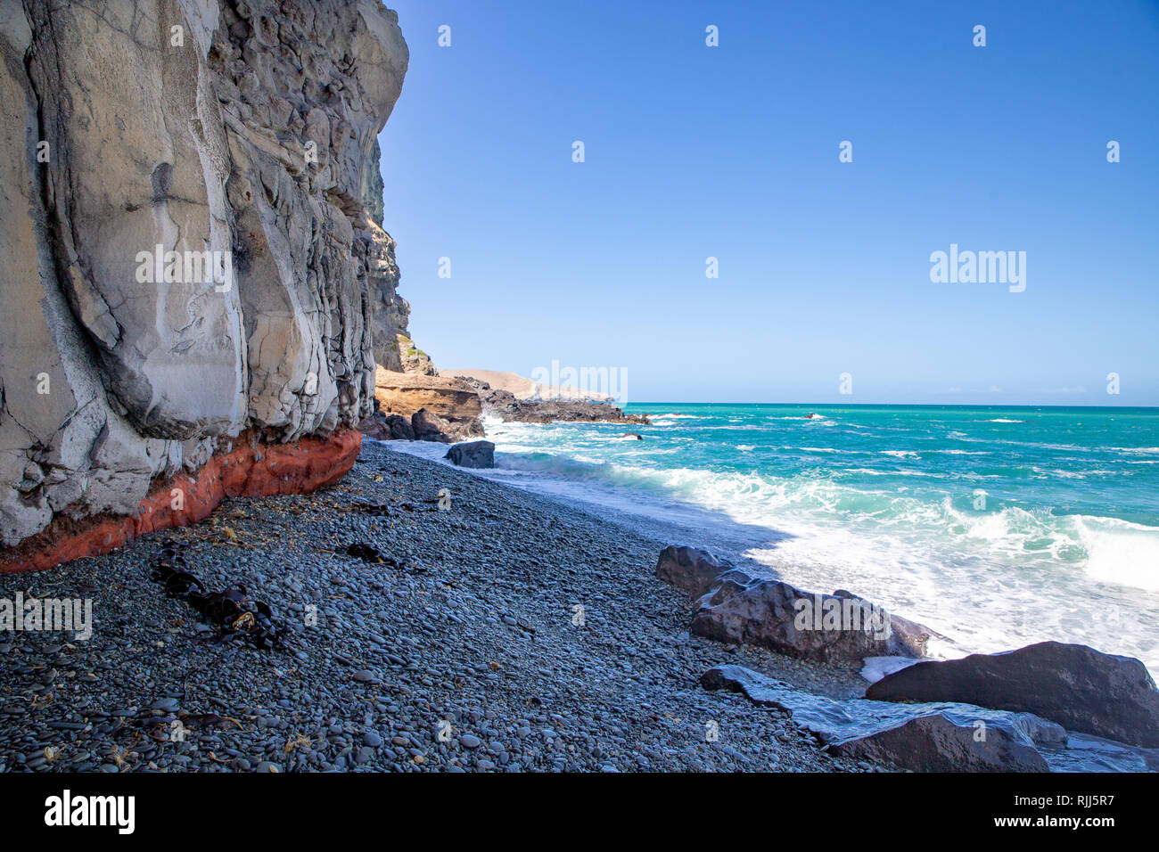 A beautiful aqua sea meets the basalt cliffs at Birdlings Flat ...