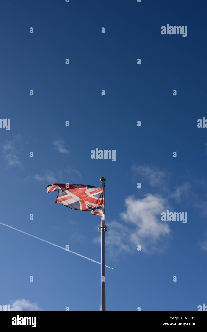 Backlit Union jack flag fluttering in the breeze, with blue sky ...